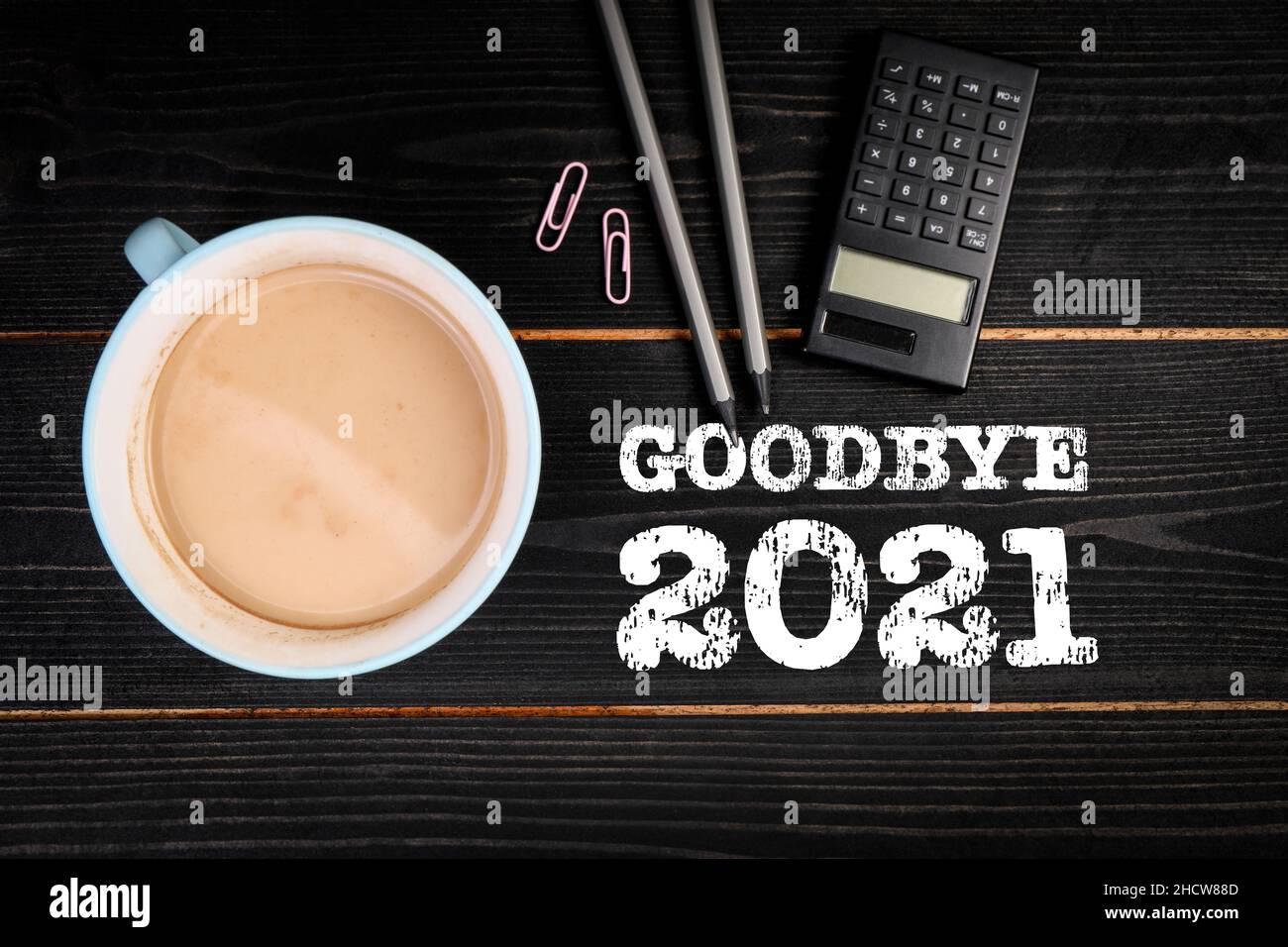 Goodbye 2021. Coffee mug, calculator and pencils on a black wooden ...