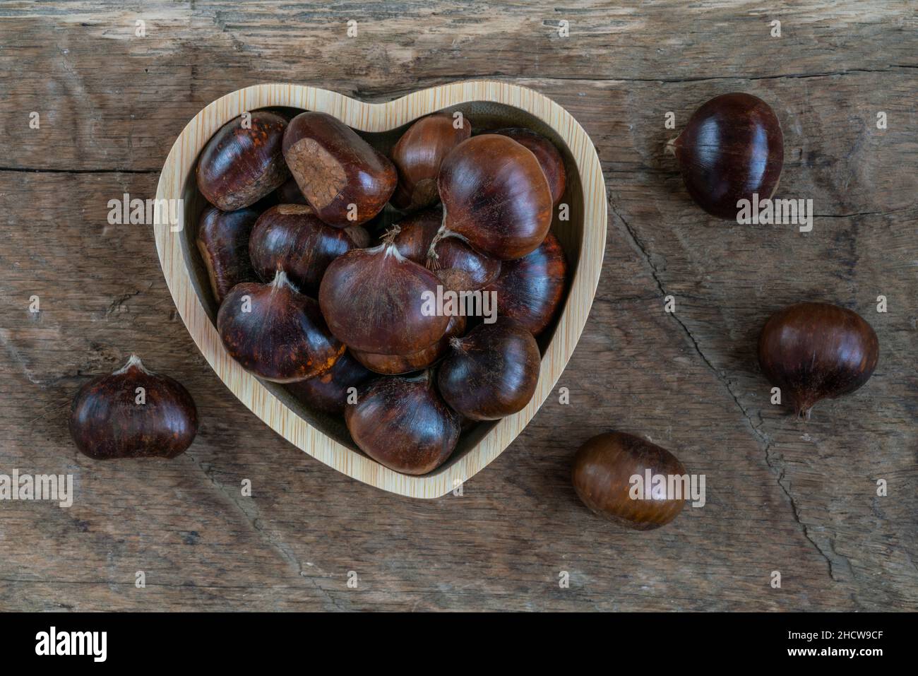 chestnuts, ripe and raw chestnut fruits in a heart shaped bowl on ...