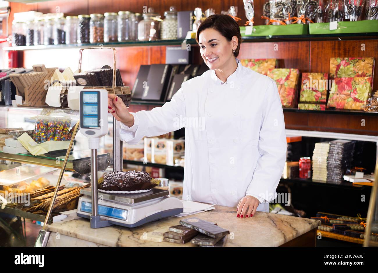 Shop assistant using scales for festive cake Stock Photo - Alamy