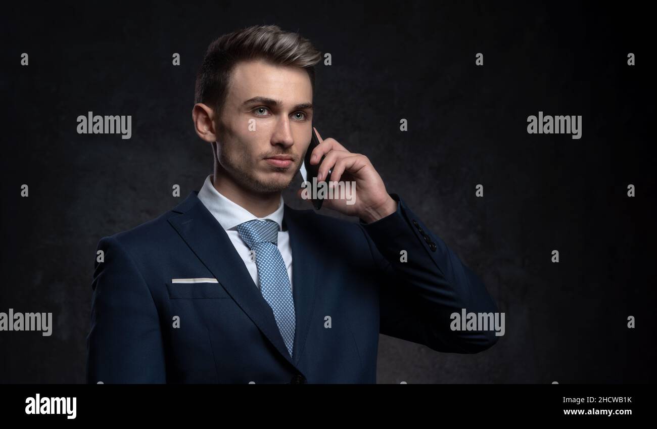 Young business man in a suit and tie talking on a mobile phone on a ...