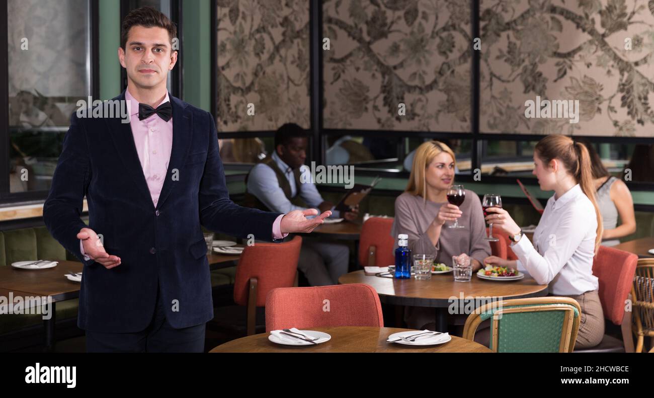 Elegant waiter with welcome gesture in restaurant hall Stock Photo - Alamy