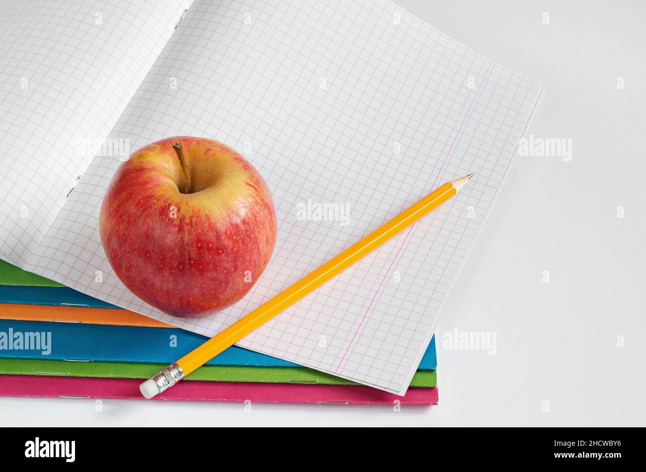 Pencil and apple on top of school notebook on white background. The ...