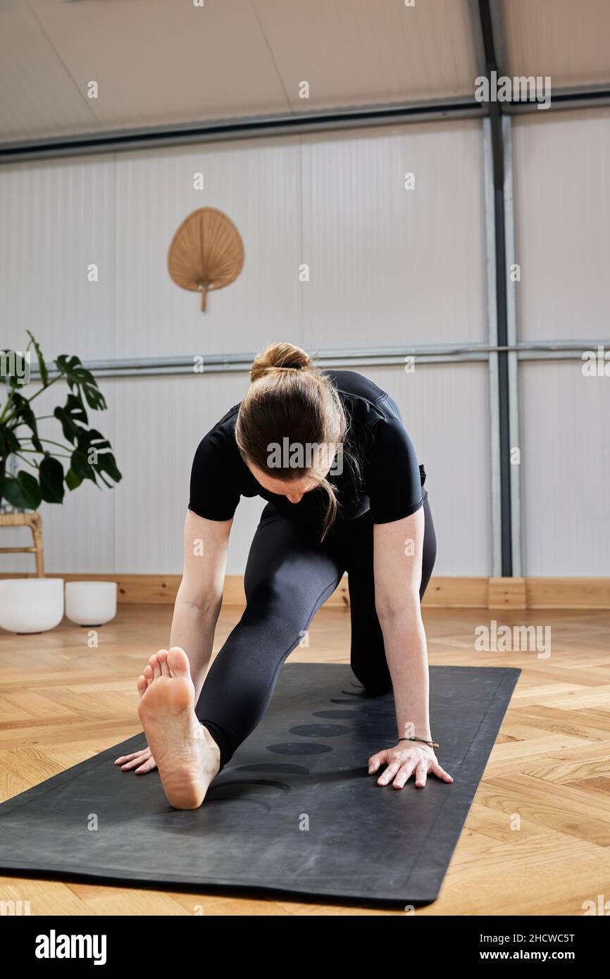 Relaxed barefoot female closing eyes and gesturing Gyan mudra while ...
