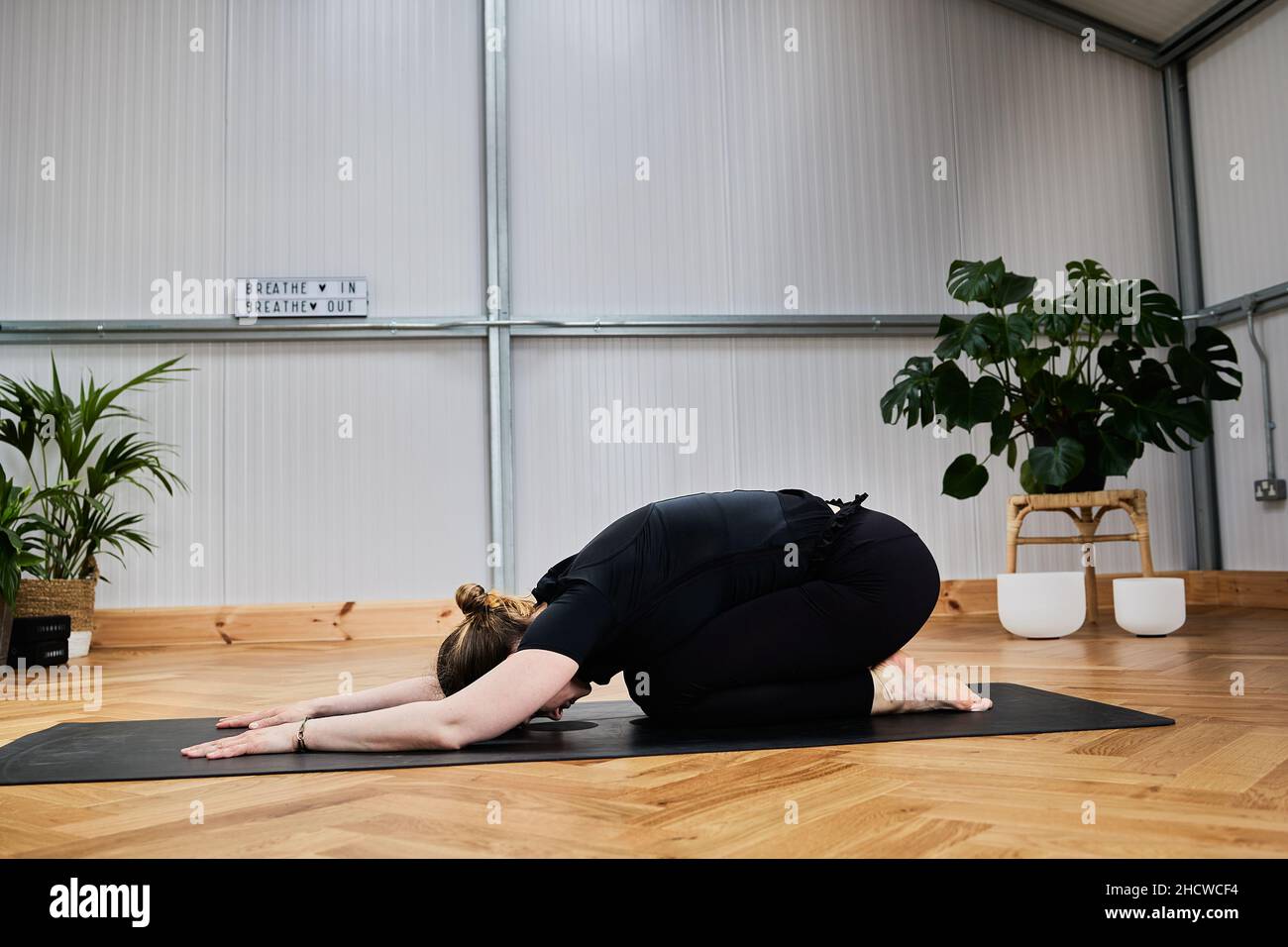 yoga trainer stretching on mat in interior studio. natural light Stock ...