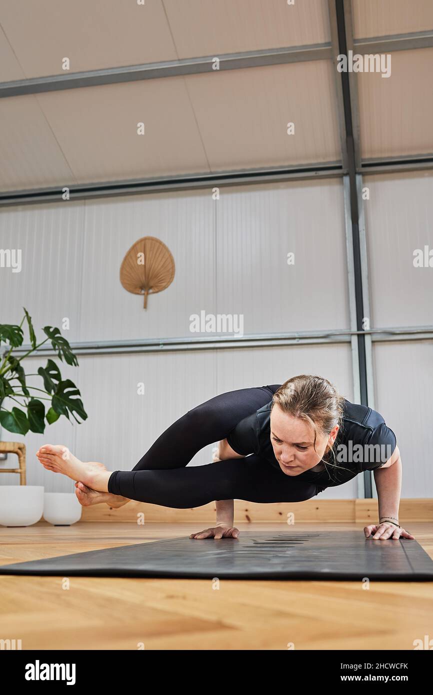 Athletic woman doing the advanced yoga posture Crow pose, kakasana ...