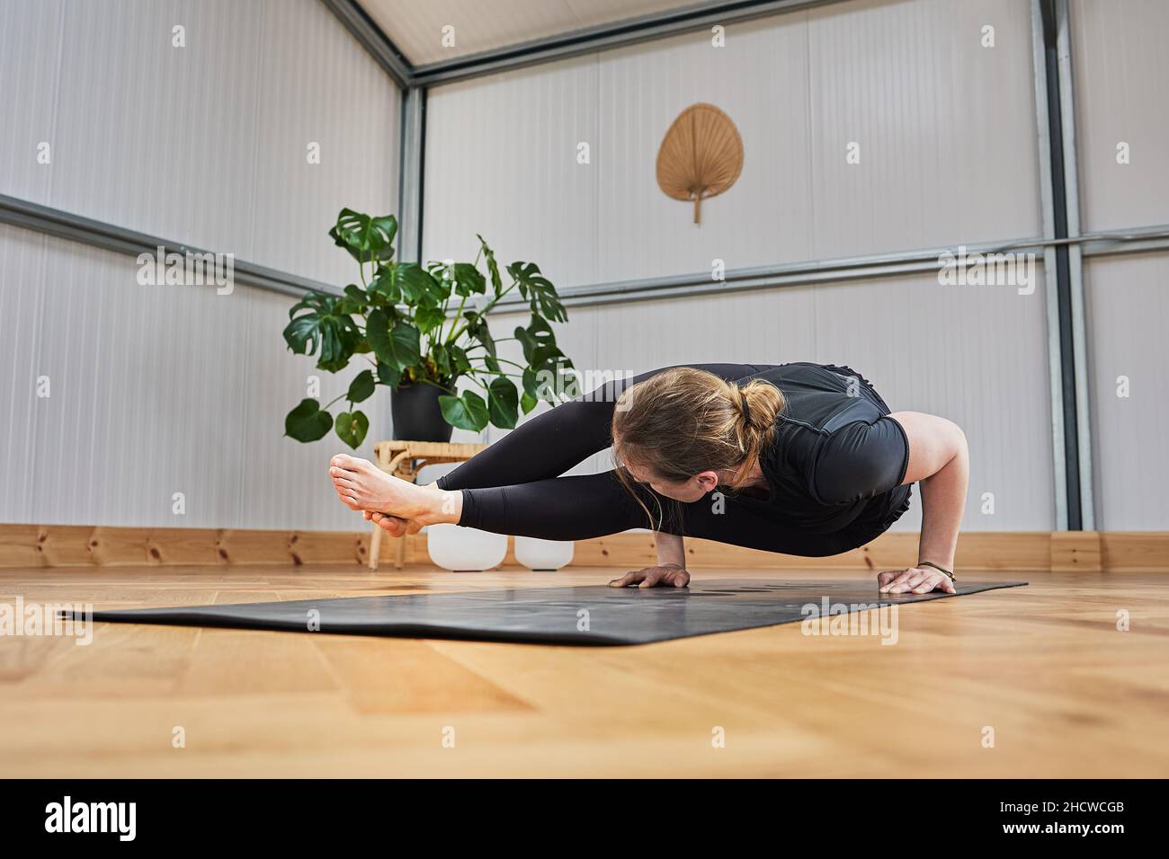 Athletic woman doing the advanced yoga posture Crow pose, kakasana ...