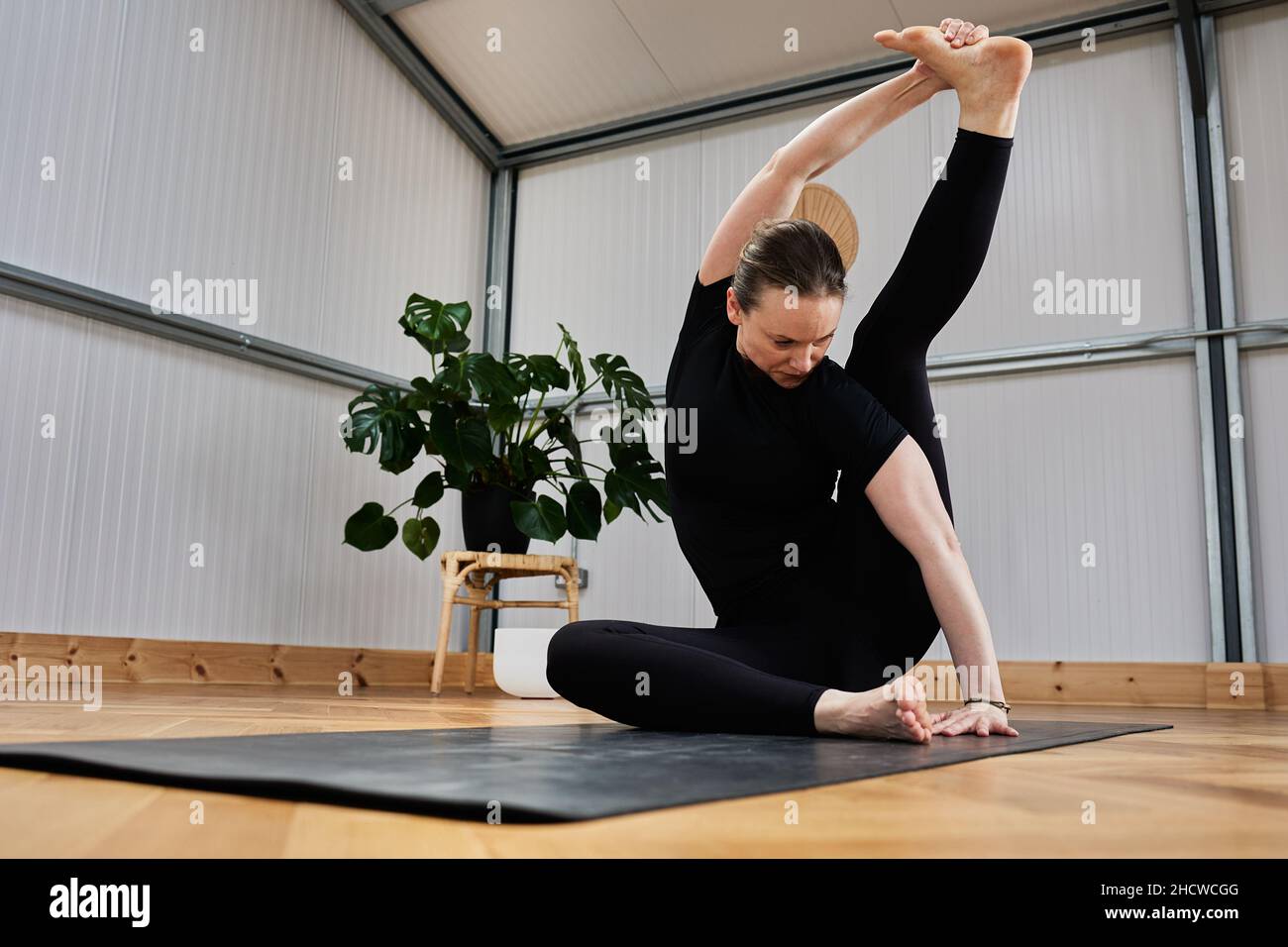 woman stretching while doing complicated yoga poses. asana concept ...