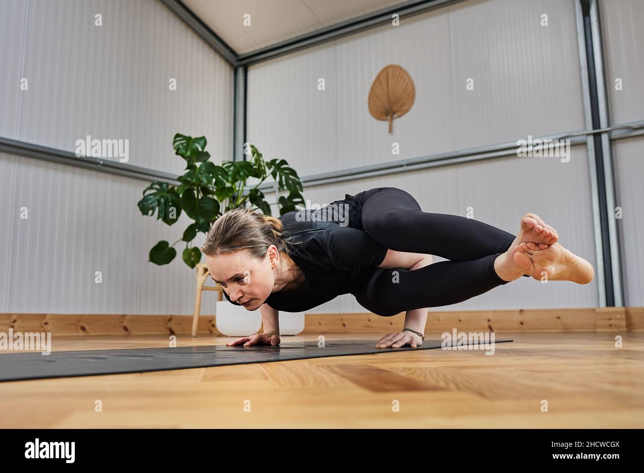 Athletic woman doing the advanced yoga posture Crow pose, kakasana ...