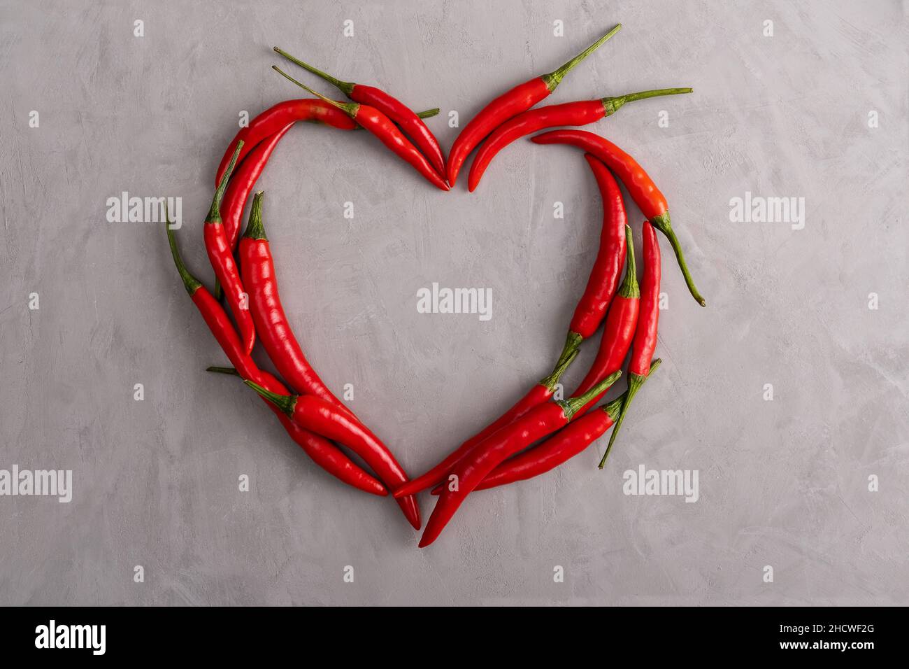 Heart-shaped contour is lined with pods of red hot peppers on gray ...