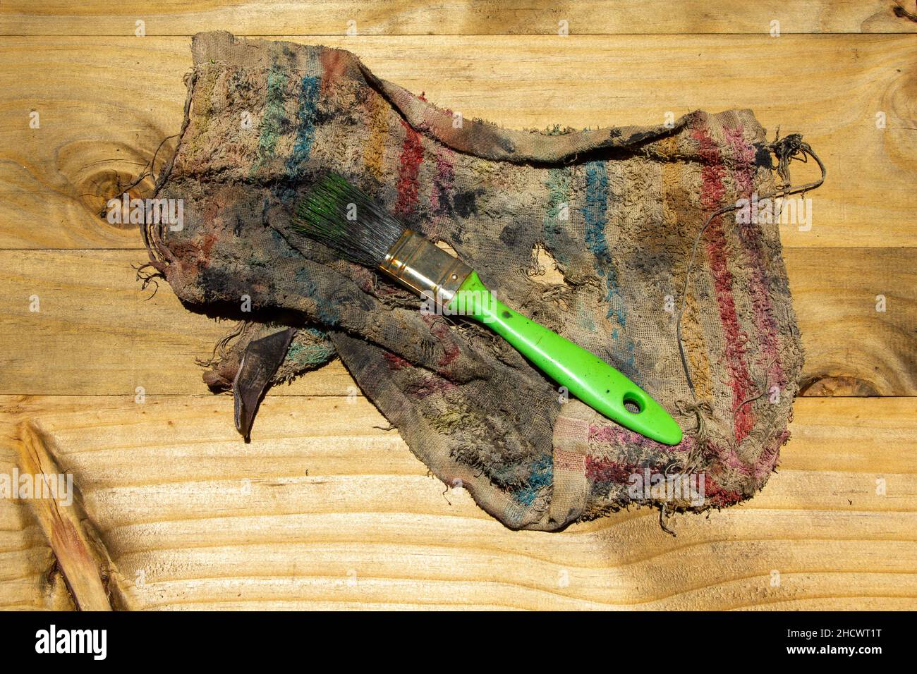 Paintbrush with a plastic green handle on a old and dirty rag cloth ...