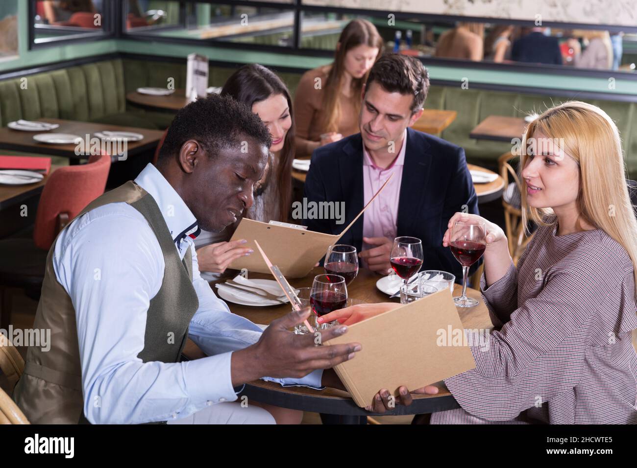 Friends choosing meal from restaurant menu Stock Photo - Alamy