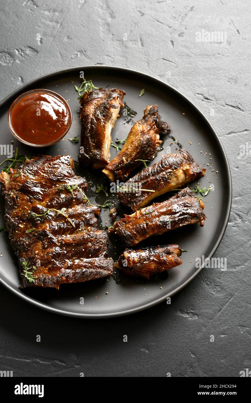 Grilled pork ribs on plate over black stone background Stock Photo - Alamy