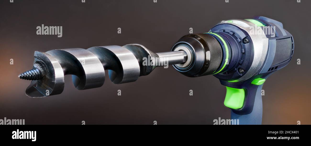 Close-up of auger bit in cordless drill on gray orange panoramic ...