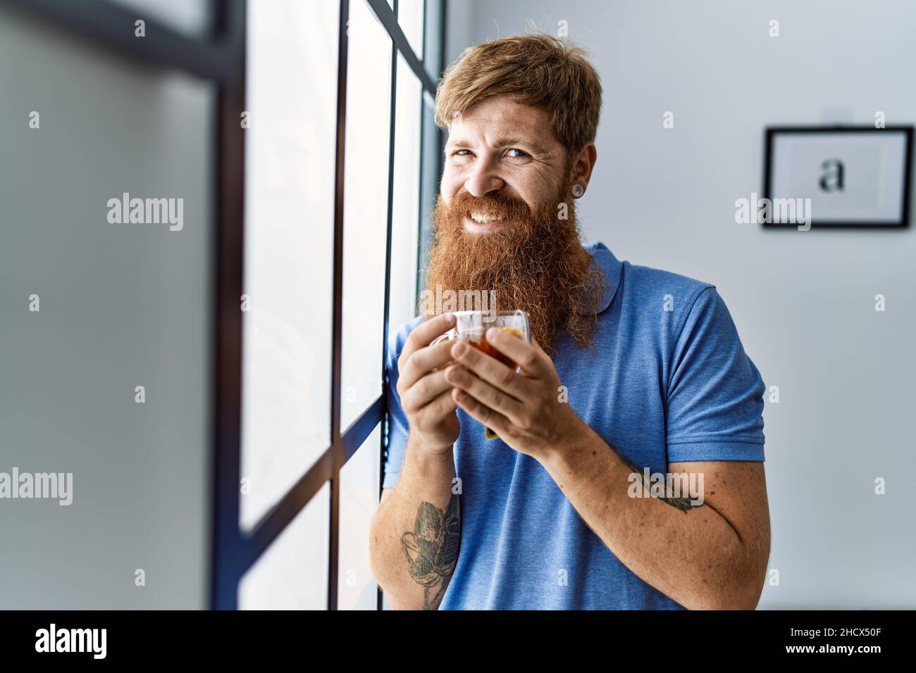 Young irish man drinking tea standing by the window at home Stock Photo ...