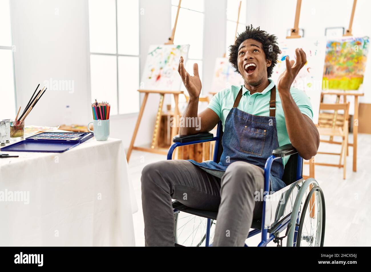 Young african american artist man sitting on wheelchair at art studio ...