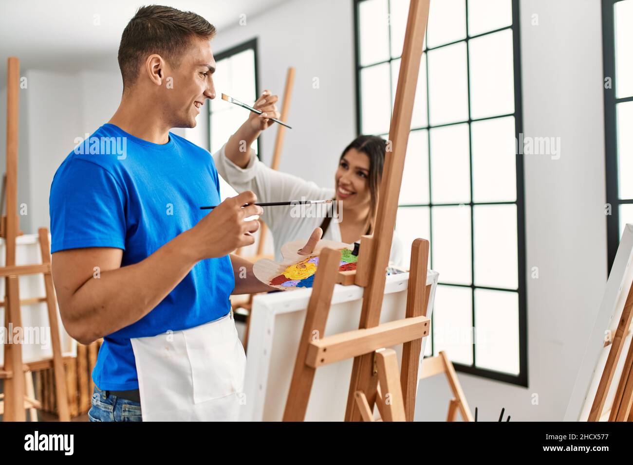 Two students smiling happy playing with paintbrush painting to each ...