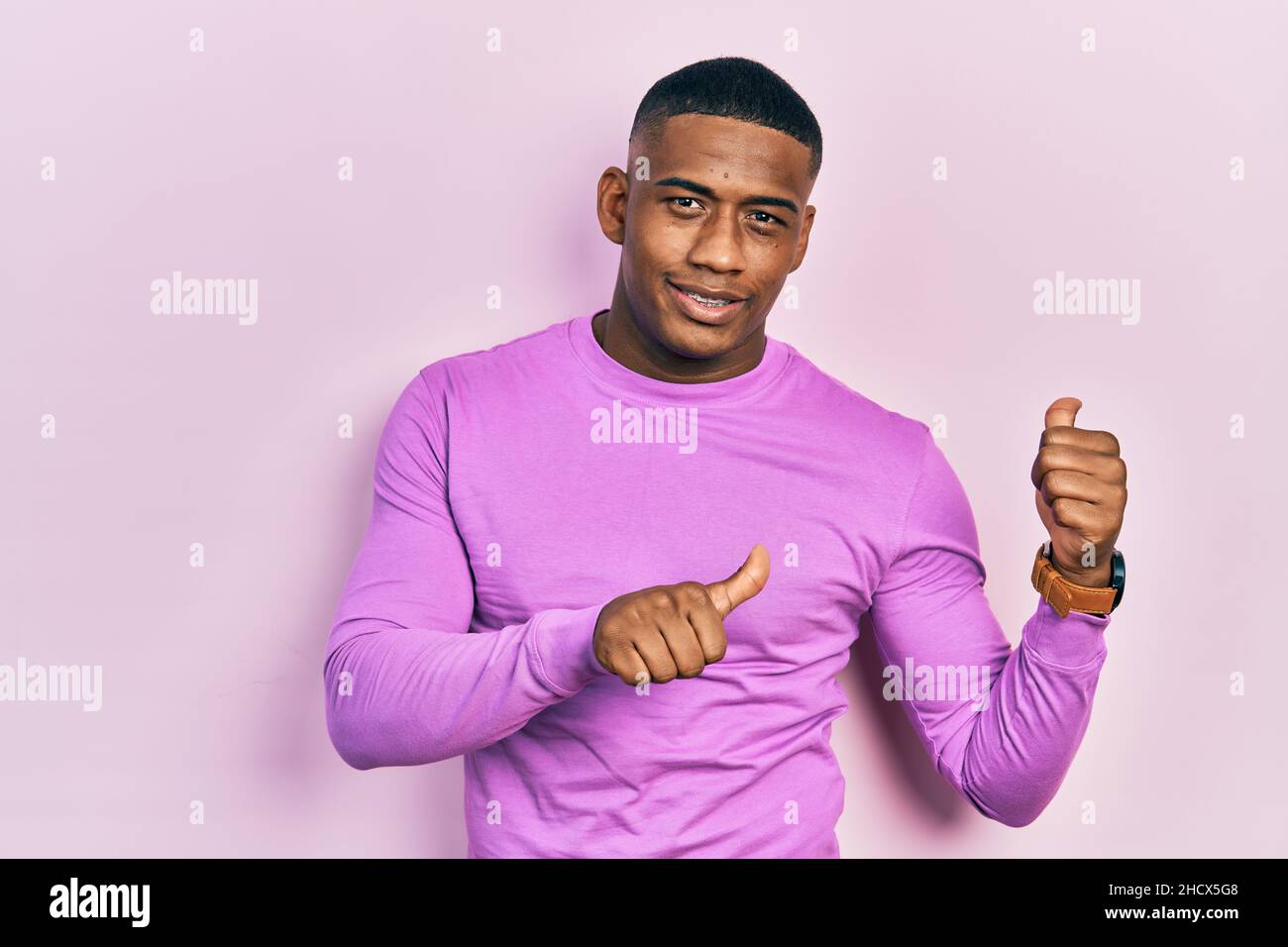 Young black man wearing casual pink sweater pointing to the back behind ...