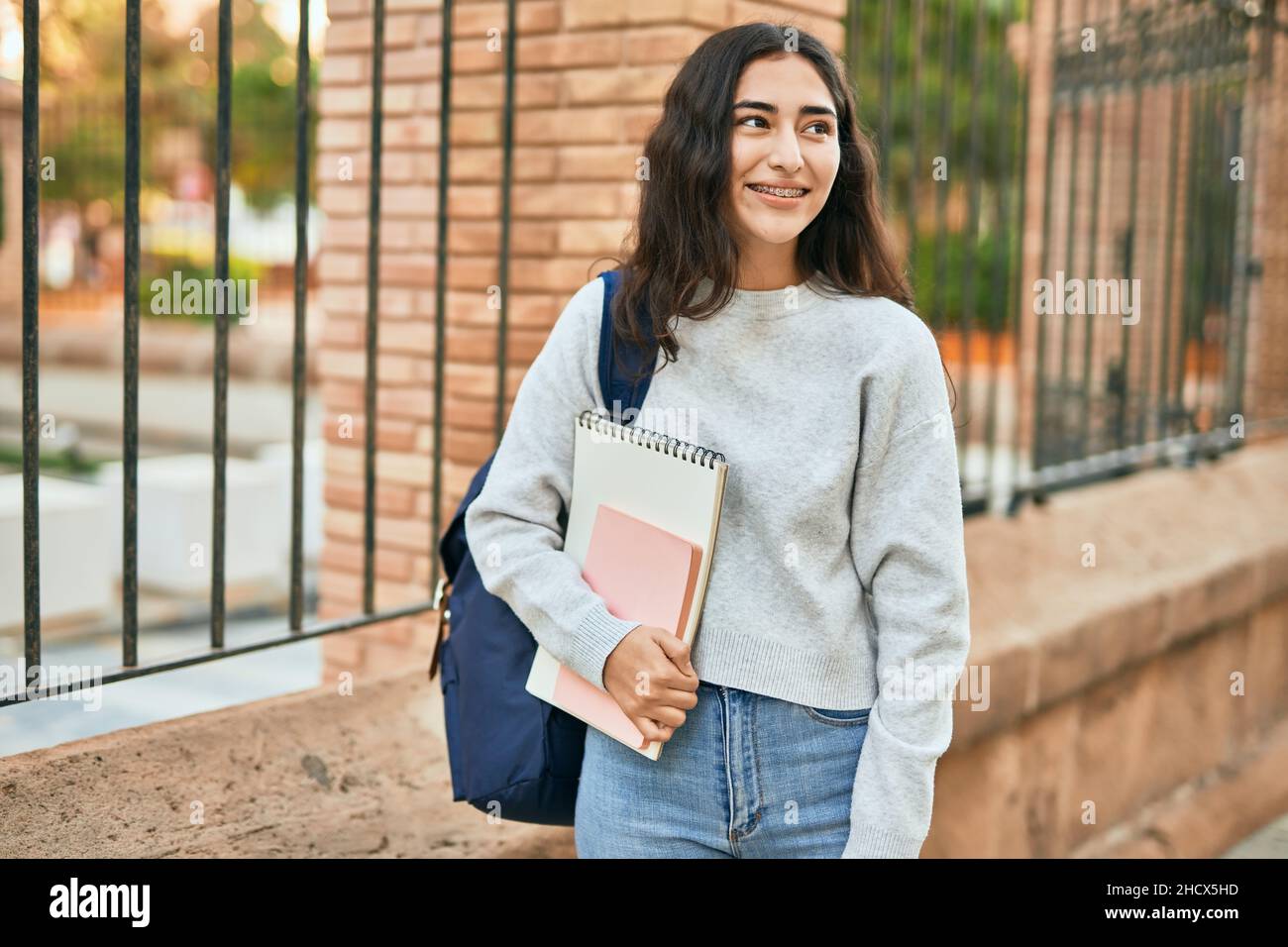 Young middle east student girl smiling happy holding book at the city ...