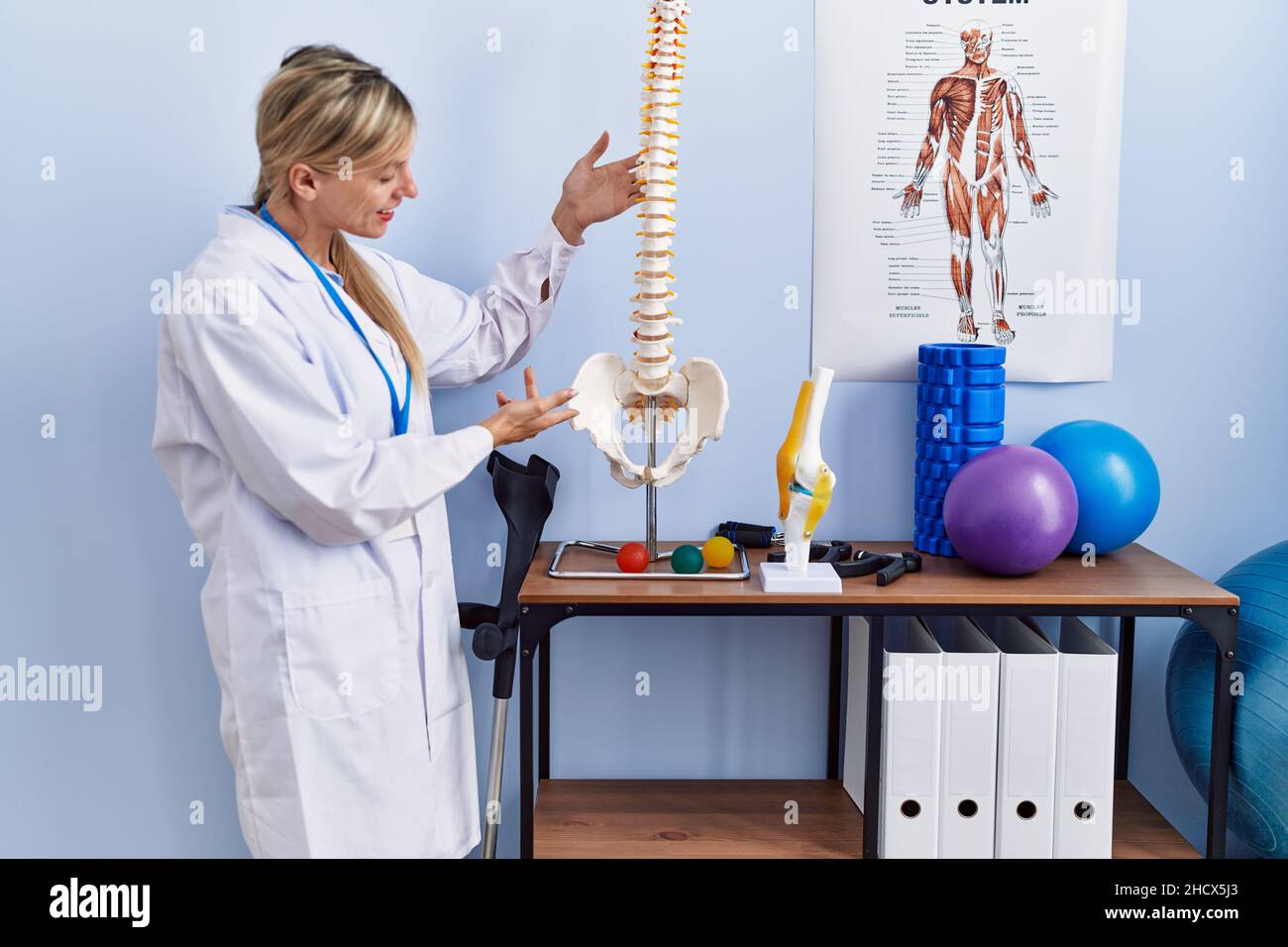 Young blonde woman wearing physiotherpist uniform pointing to ...