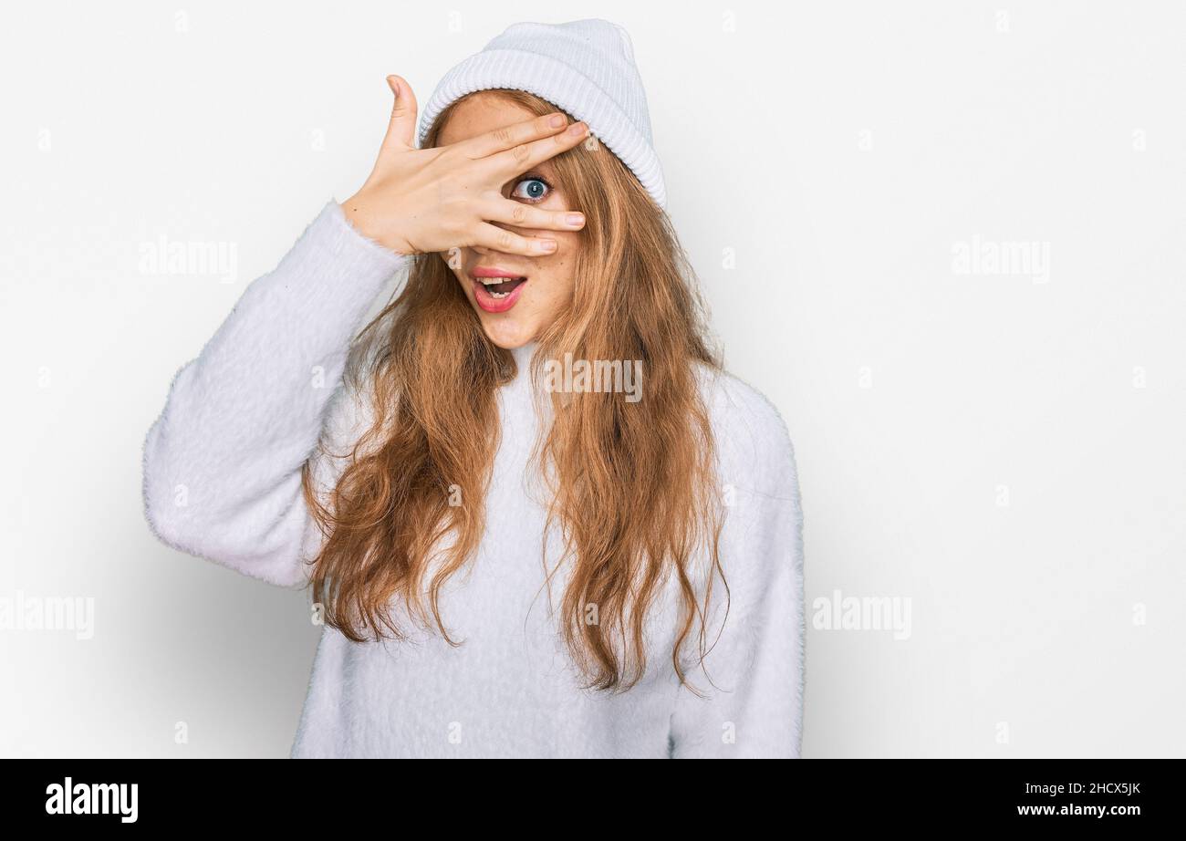 Young caucasian girl wearing wool sweater and winter cap peeking in ...