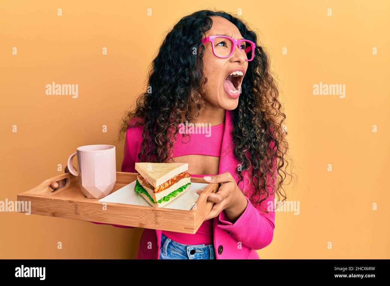Young latin woman wearing business style having breakfast angry and mad ...