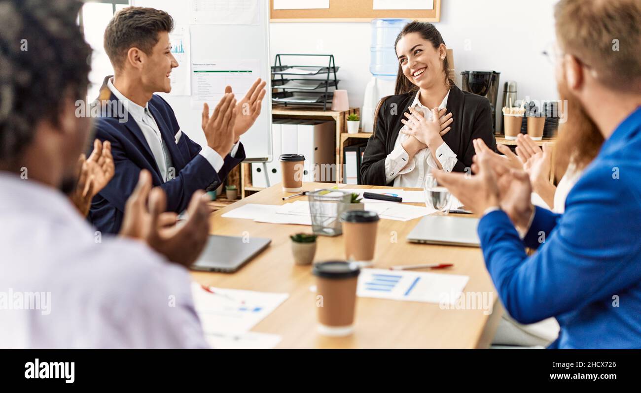 Group of business workers smiling and clapping to partner at the office ...