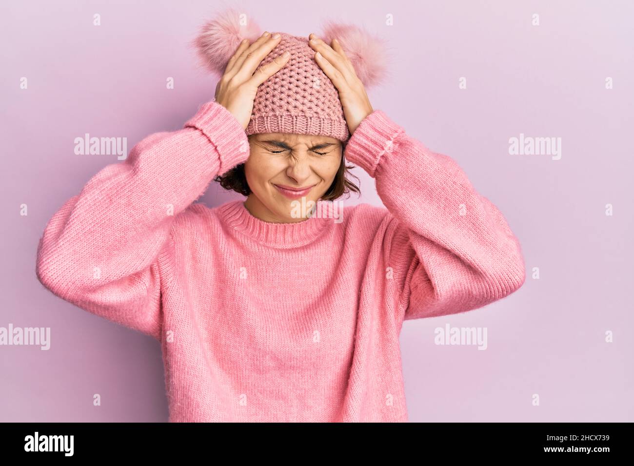 Young brunette woman wearing cute wool cap suffering from headache ...