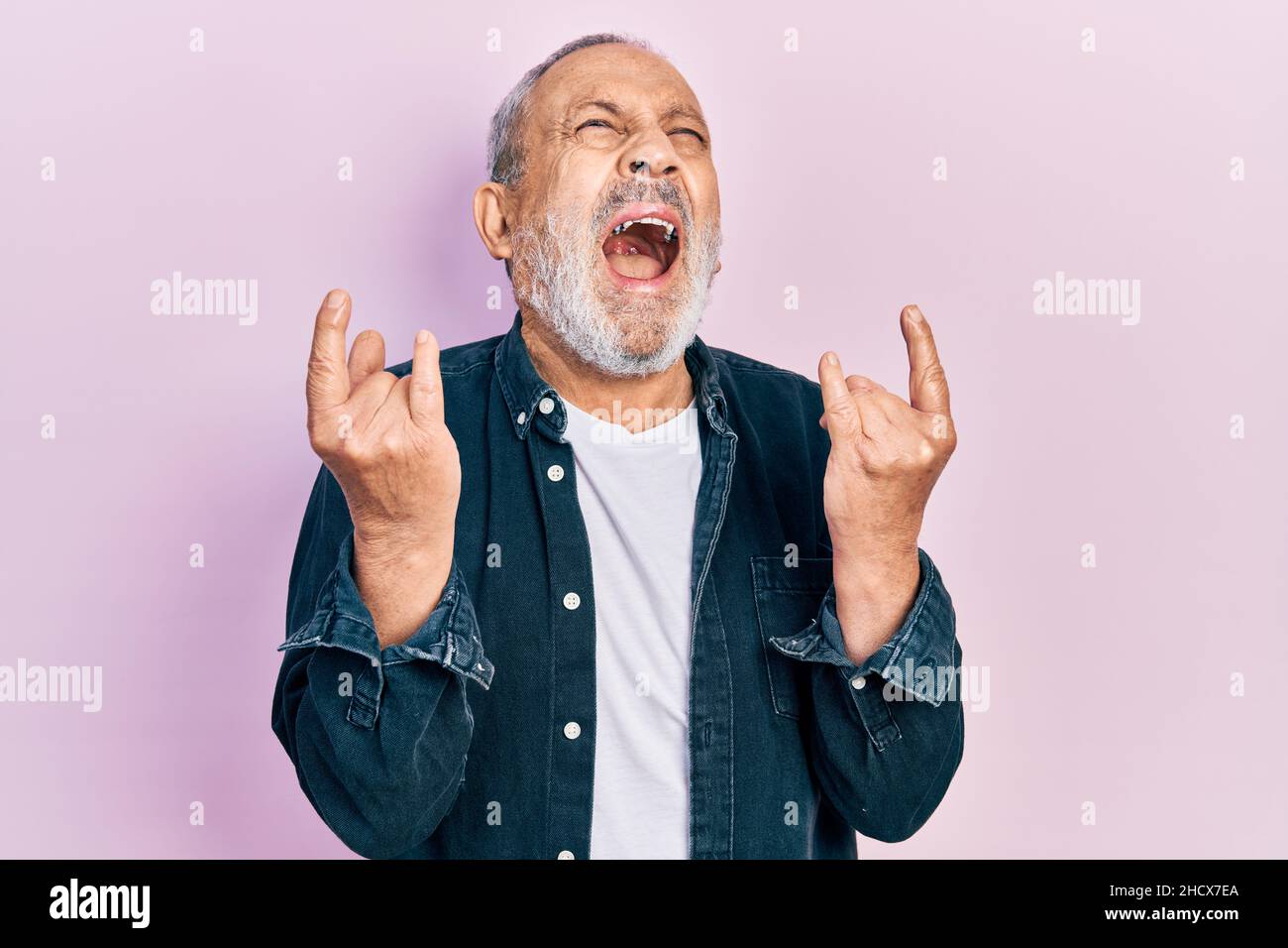 Handsome senior man with beard doing rock gesture angry and mad ...