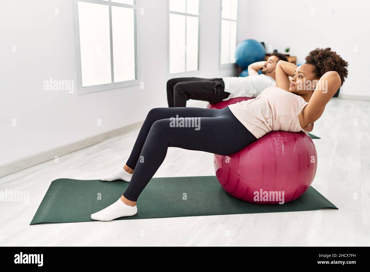 Young african american woman and hispanic man exercising at pilates ...