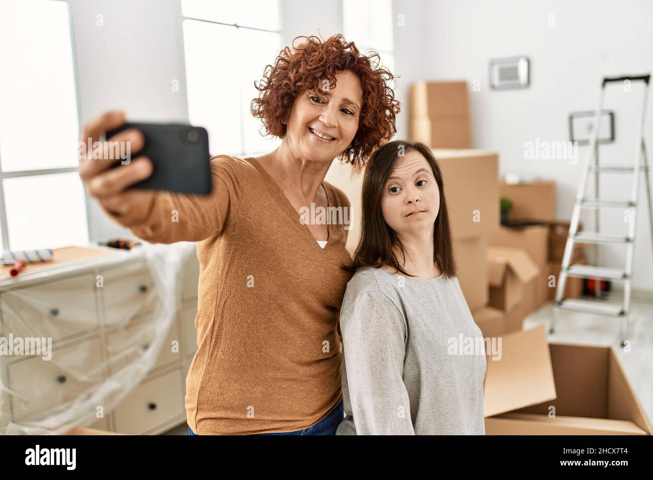 Mature mother and down syndrome daughter moving to a new home, standing ...