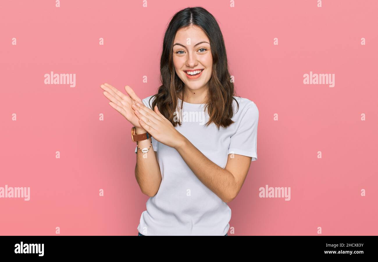 Young beautiful woman wearing casual white t shirt clapping and ...