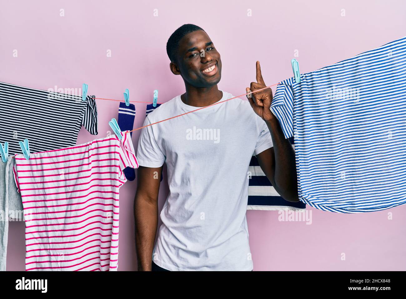 Young african american man washing clothes at clothesline smiling with ...