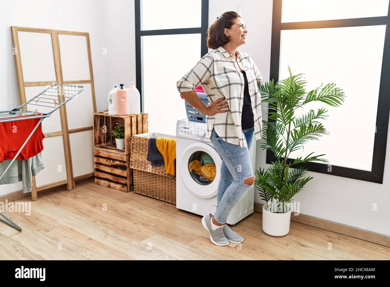Middle age hispanic woman waiting for washing machine at laundry room ...