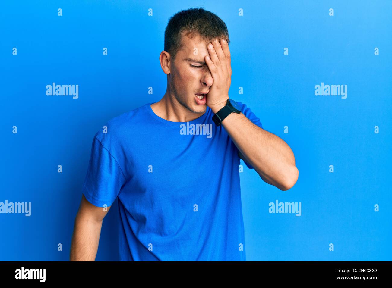 Young caucasian man wearing casual blue t shirt yawning tired covering ...