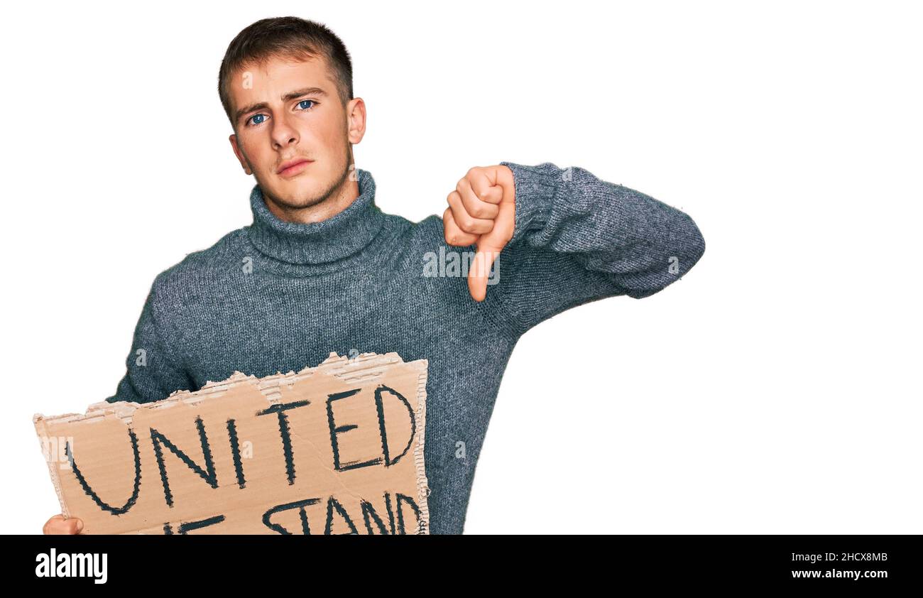 Young blond man holding united we stand banner with angry face ...