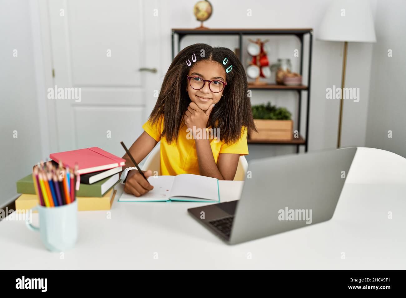 Young african american girl doing homework at home looking confident at ...