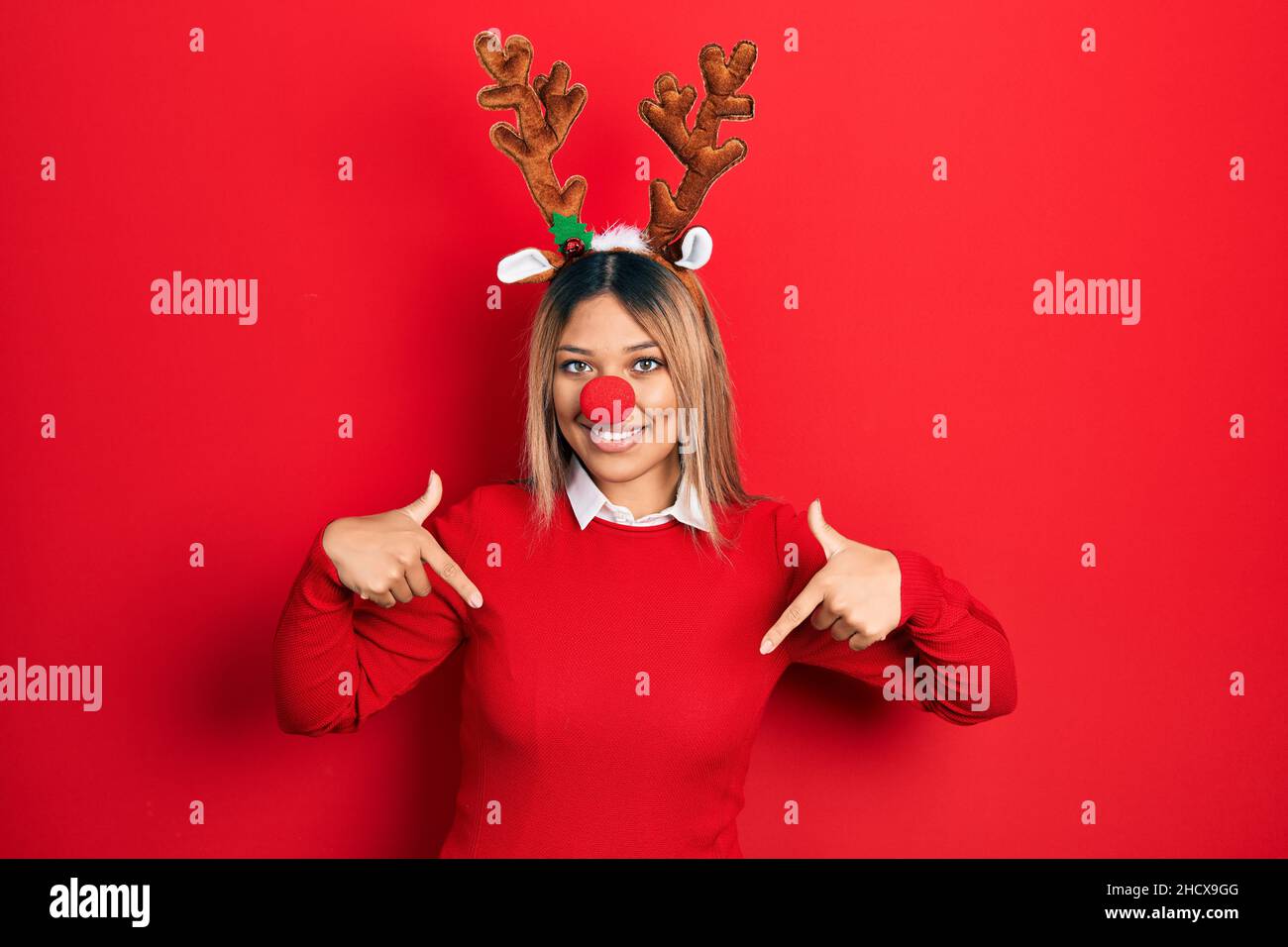 Beautiful hispanic woman wearing deer christmas hat and red nose ...