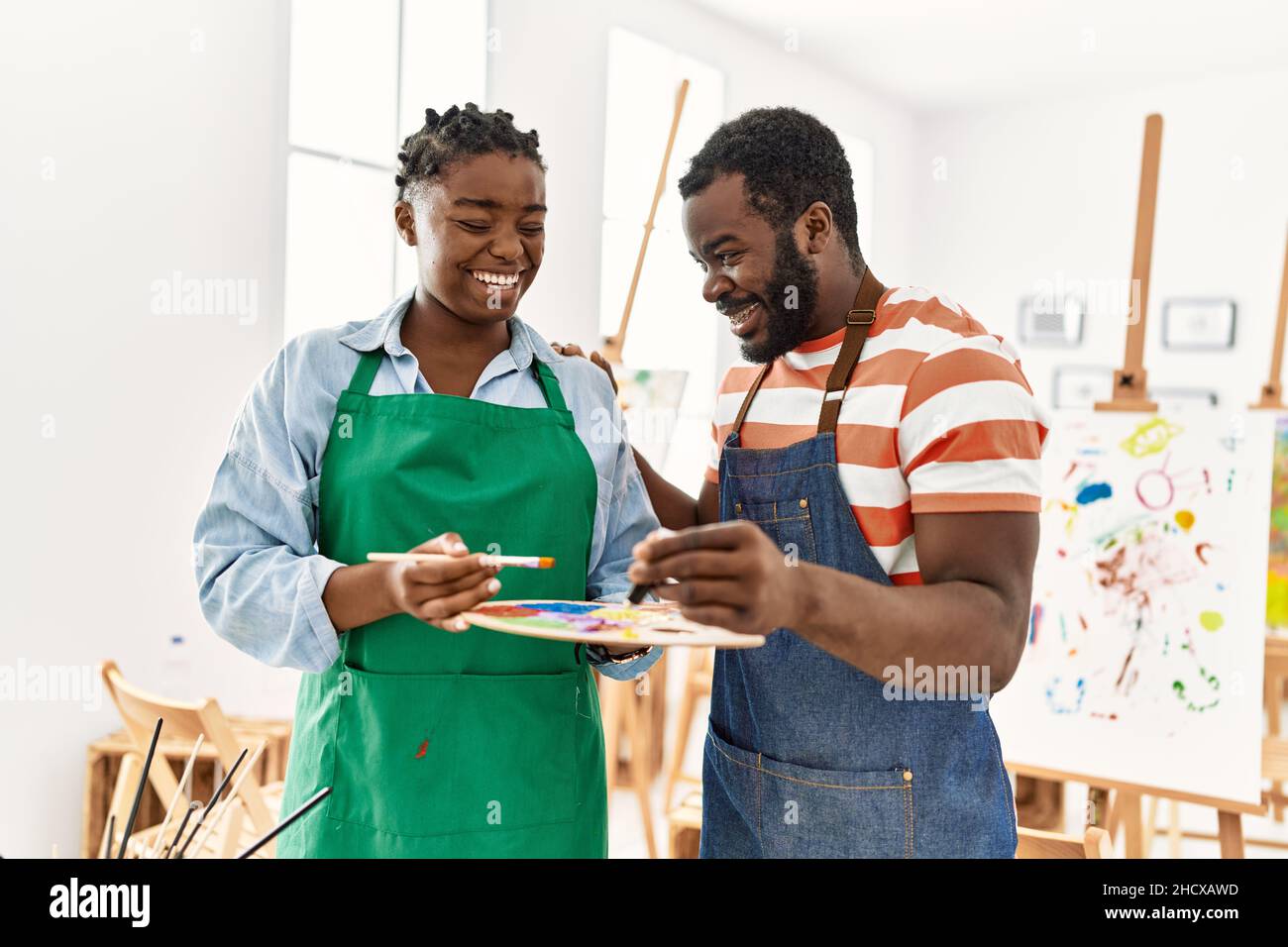 African american painter couple smiling happy holding paintbrush and ...