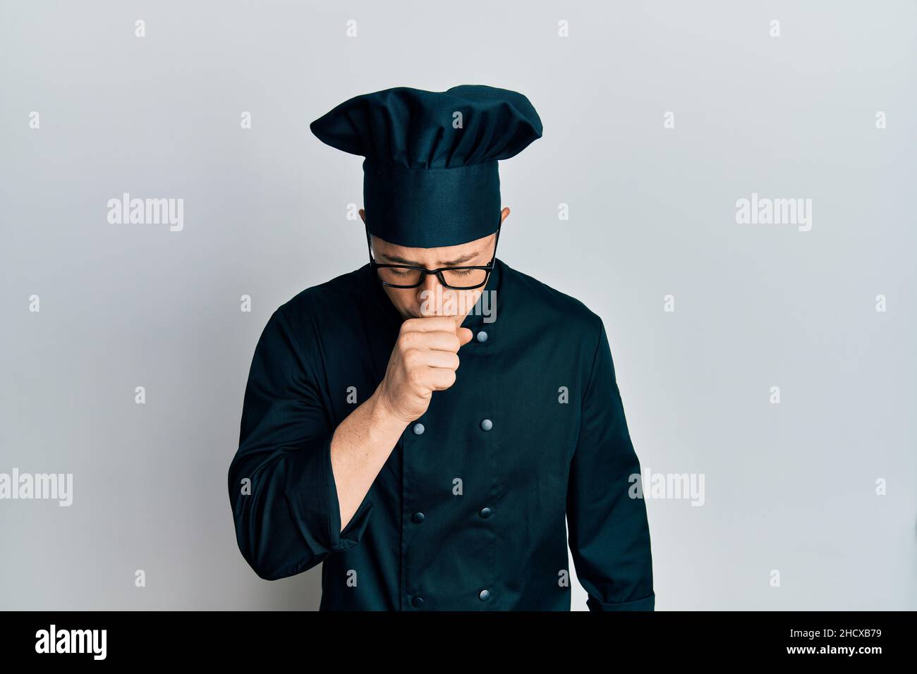 Handsome young man wearing professional cook uniform and hat feeling ...