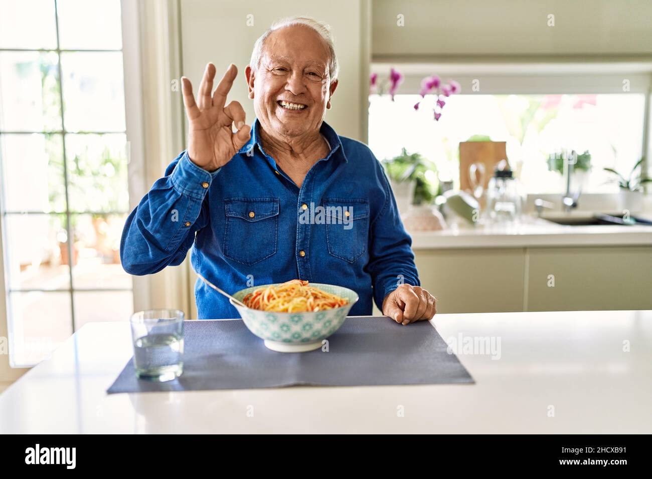 Senior man with grey hair eating pasta spaghetti at home smiling ...