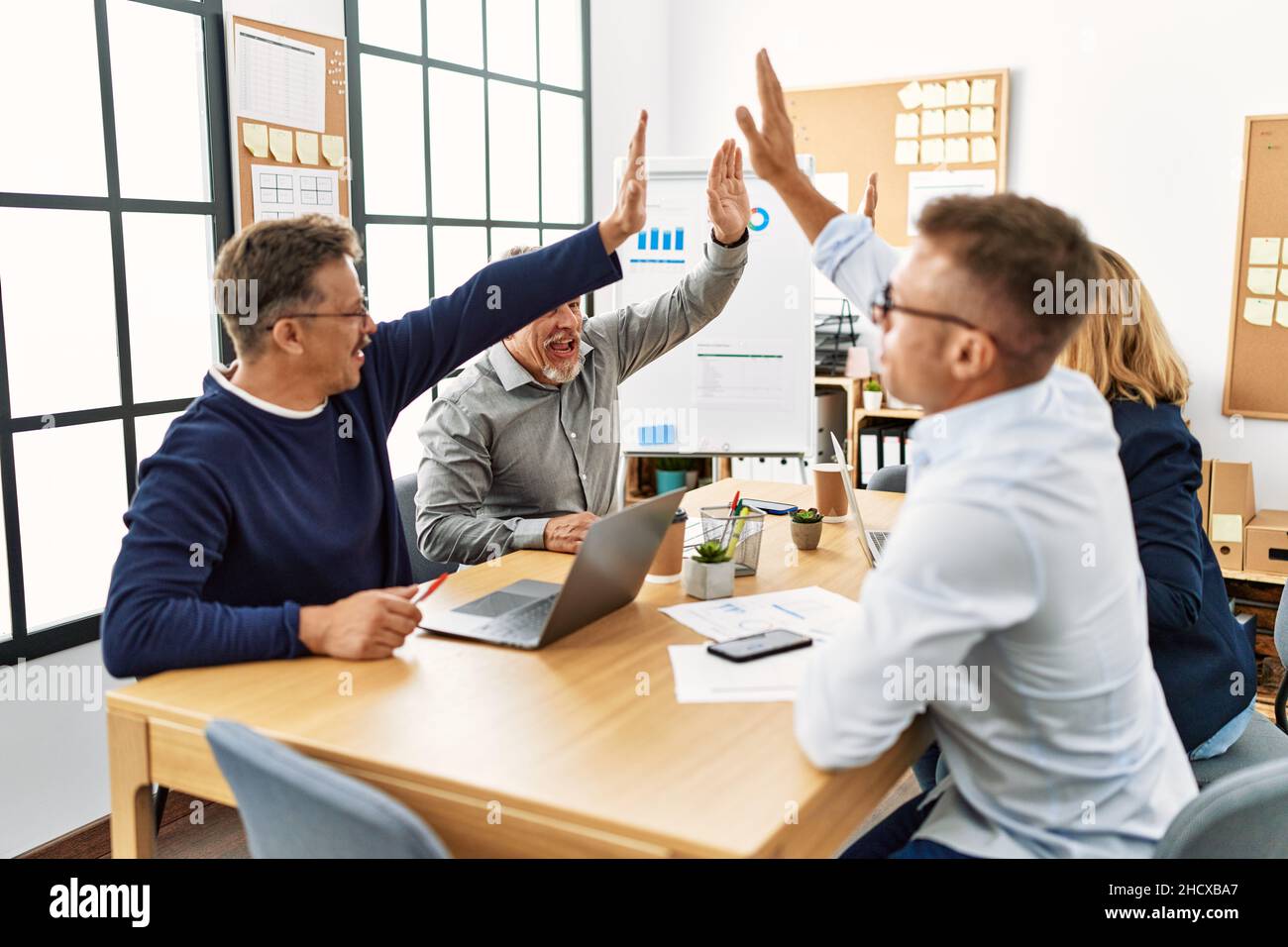 Group of middle age business workers high five at the office Stock ...