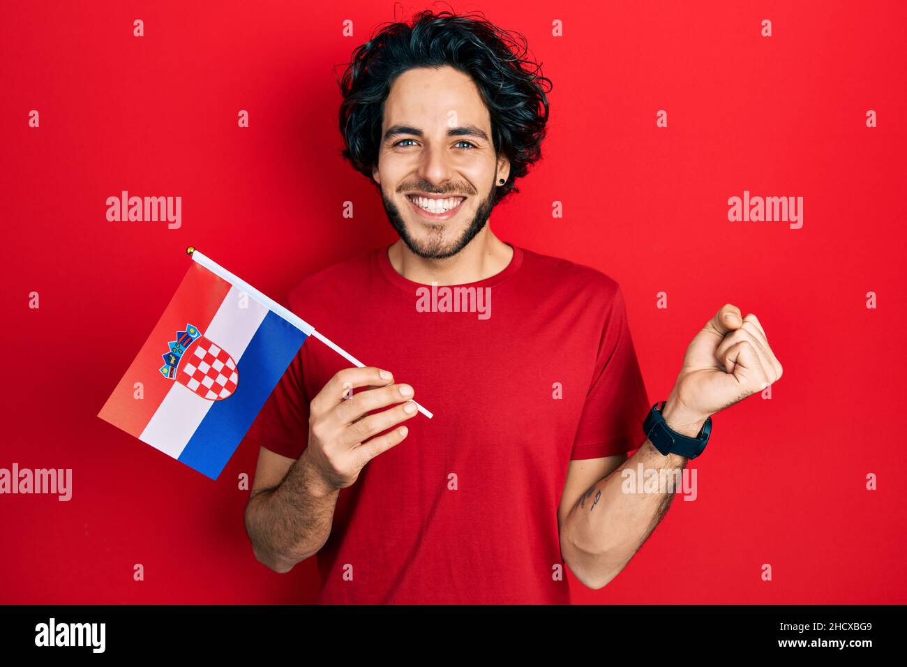 Handsome hispanic man holding croatia flag screaming proud, celebrating ...
