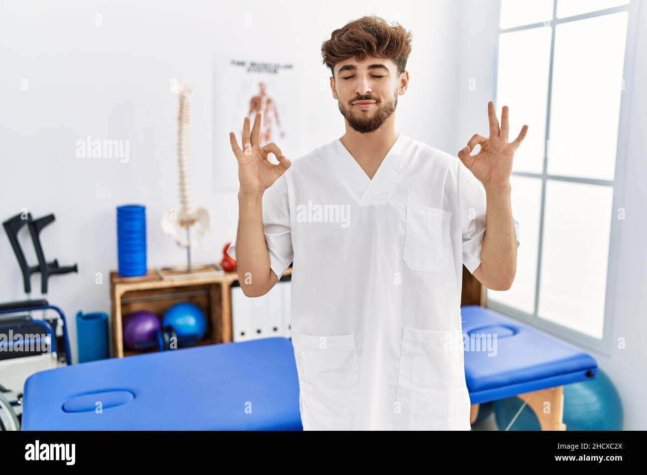 Young arab man working at pain recovery clinic relax and smiling with ...