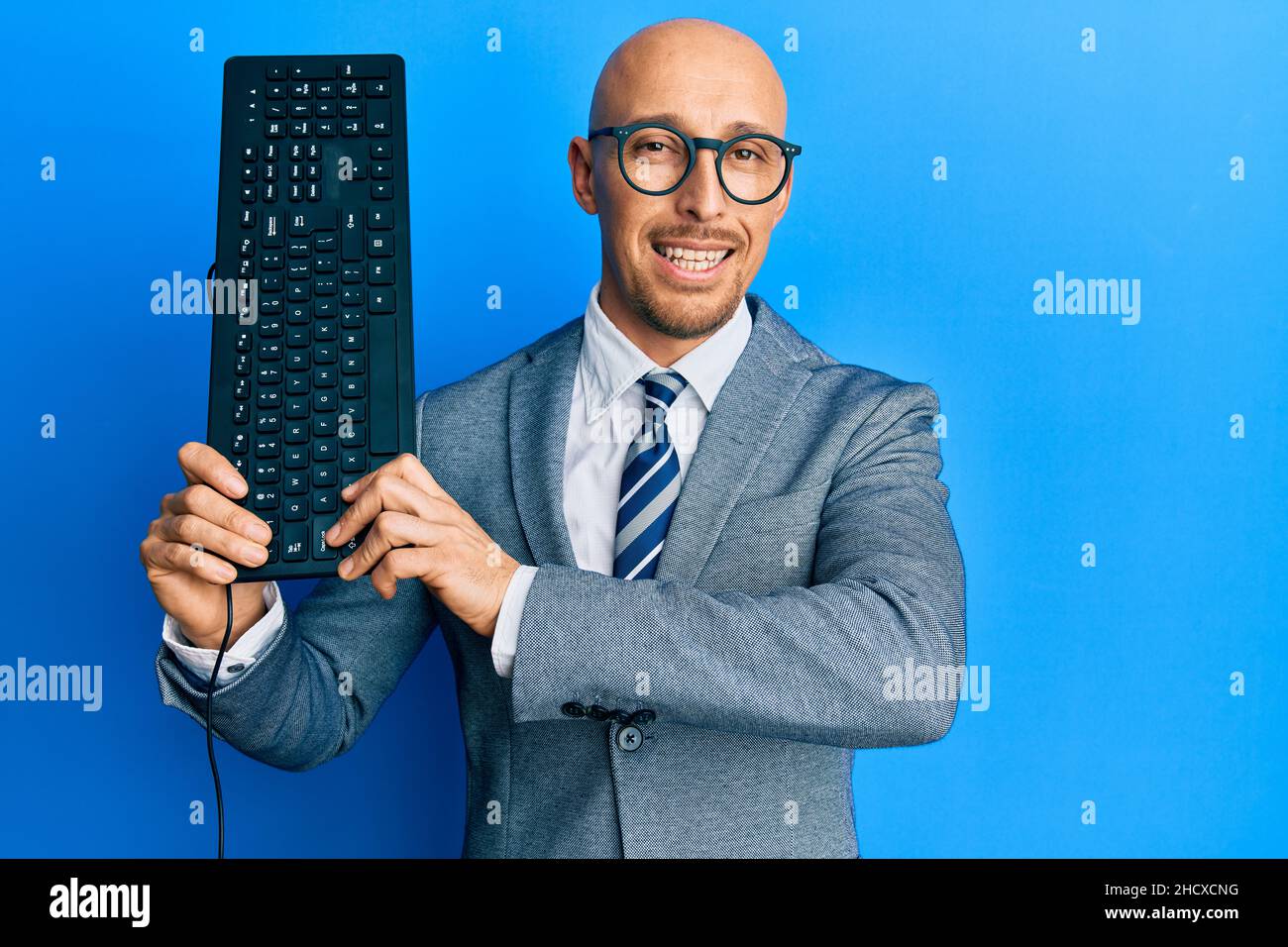 Bald man with beard holding keyboard smiling with a happy and cool ...