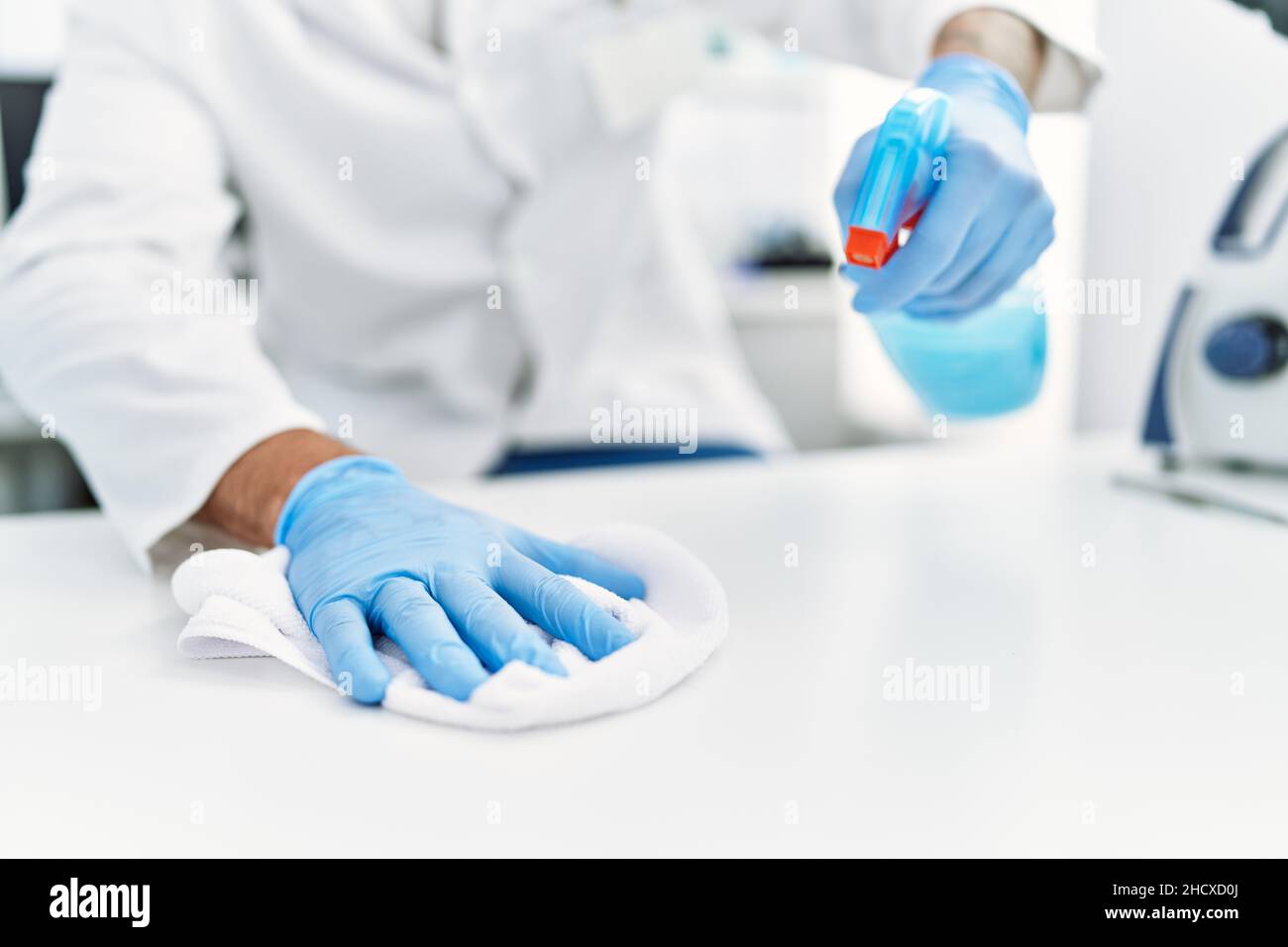 Handsome hispanic man working as scientific cleaning the table at ...