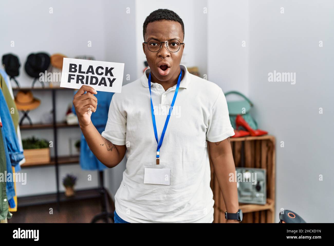 Young african man holding black friday banner at retail shop scared and ...