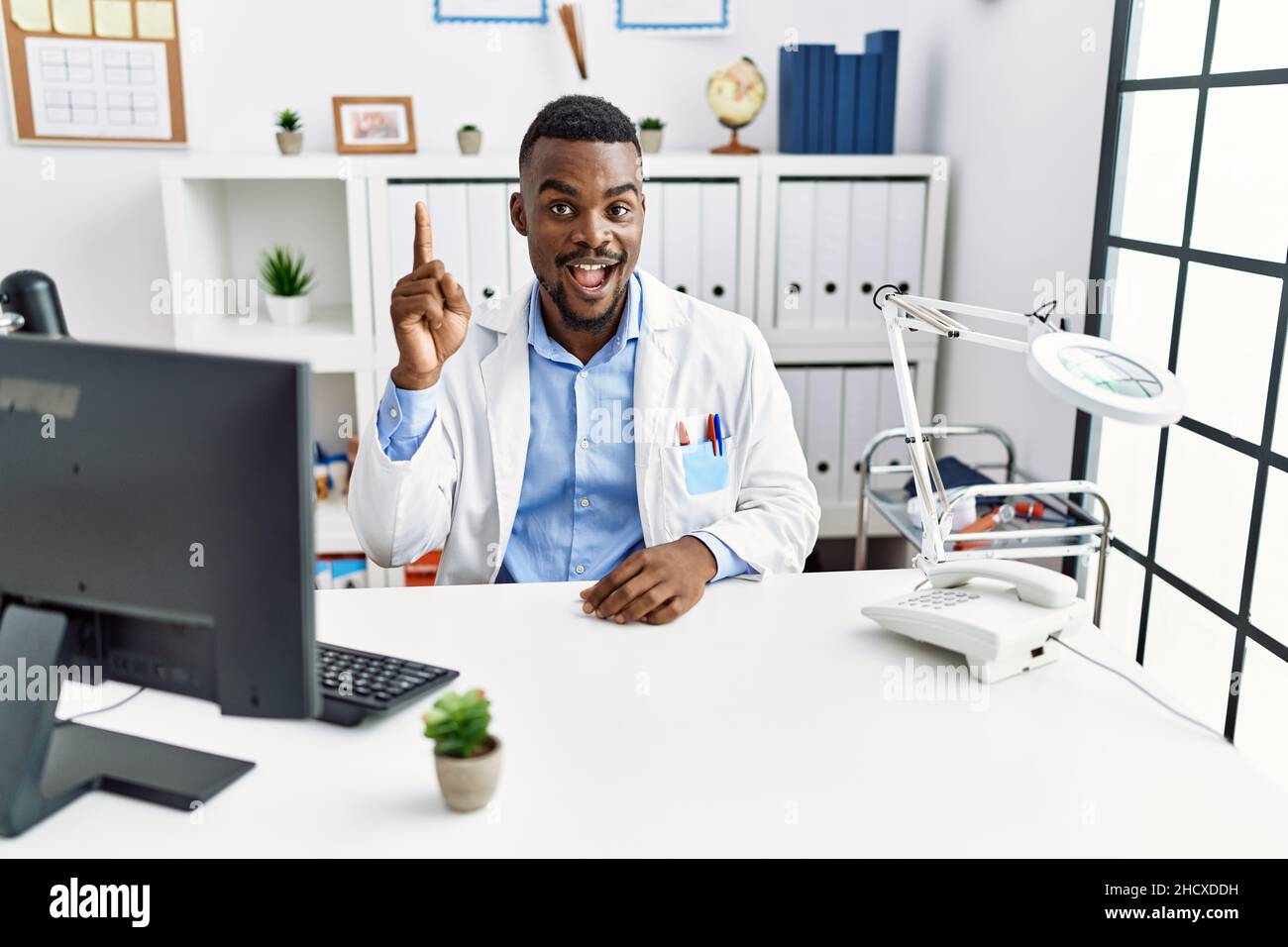 Young african doctor man wearing stethoscope at the clinic pointing ...