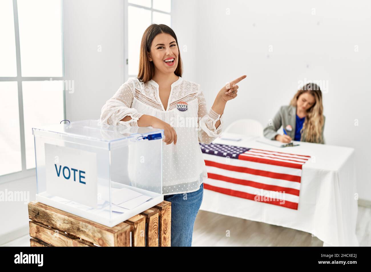 Young brunette woman voting putting envelop in ballot box smiling happy ...