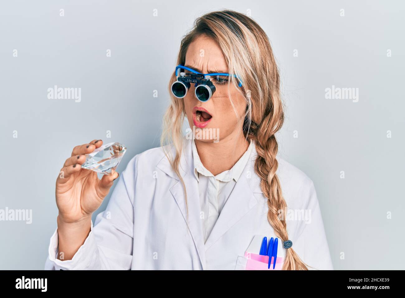 Beautiful young blonde woman holding brilliant diamond stone wearing ...