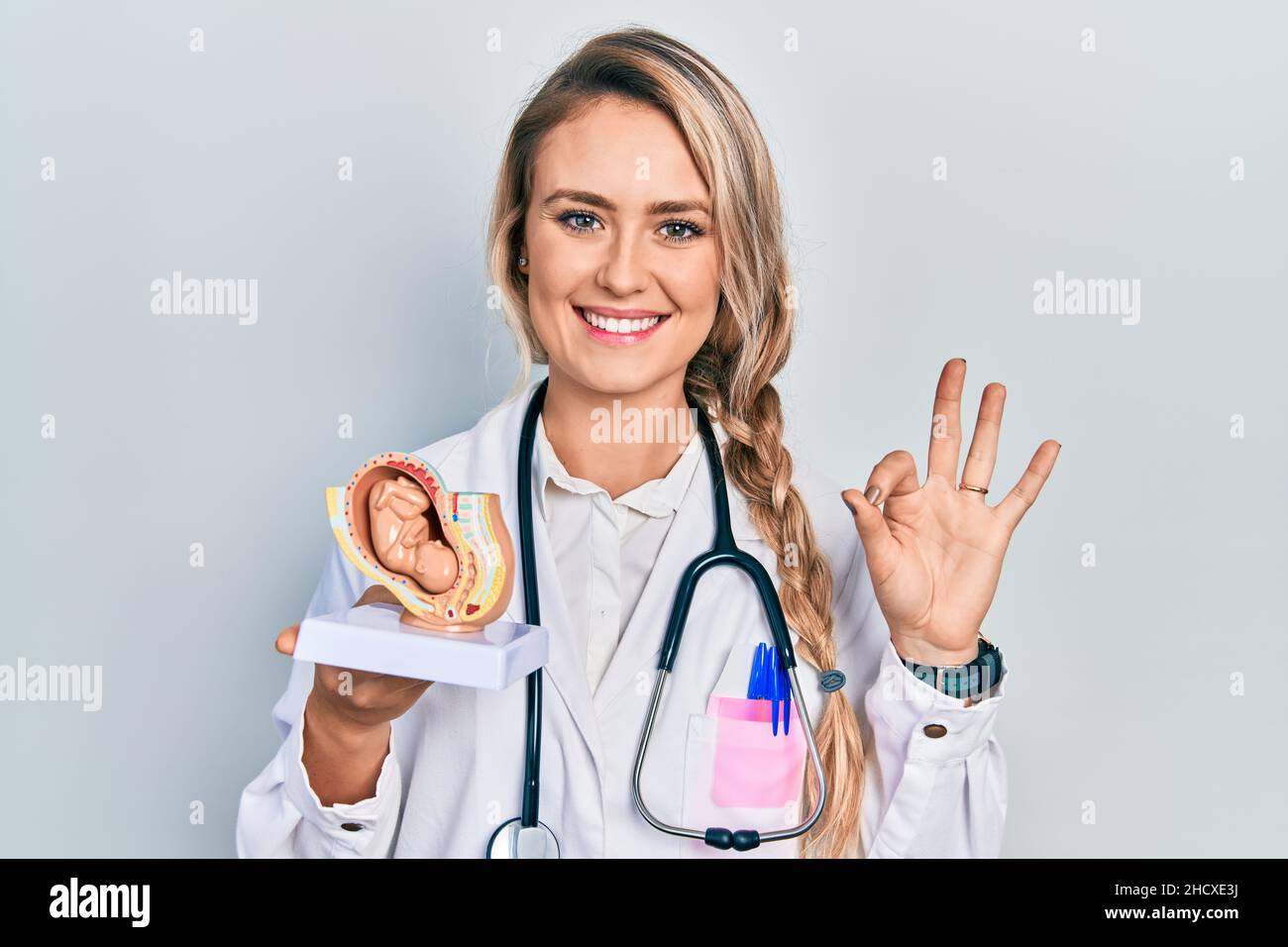 Beautiful young blonde doctor woman holding anatomical model of female ...
